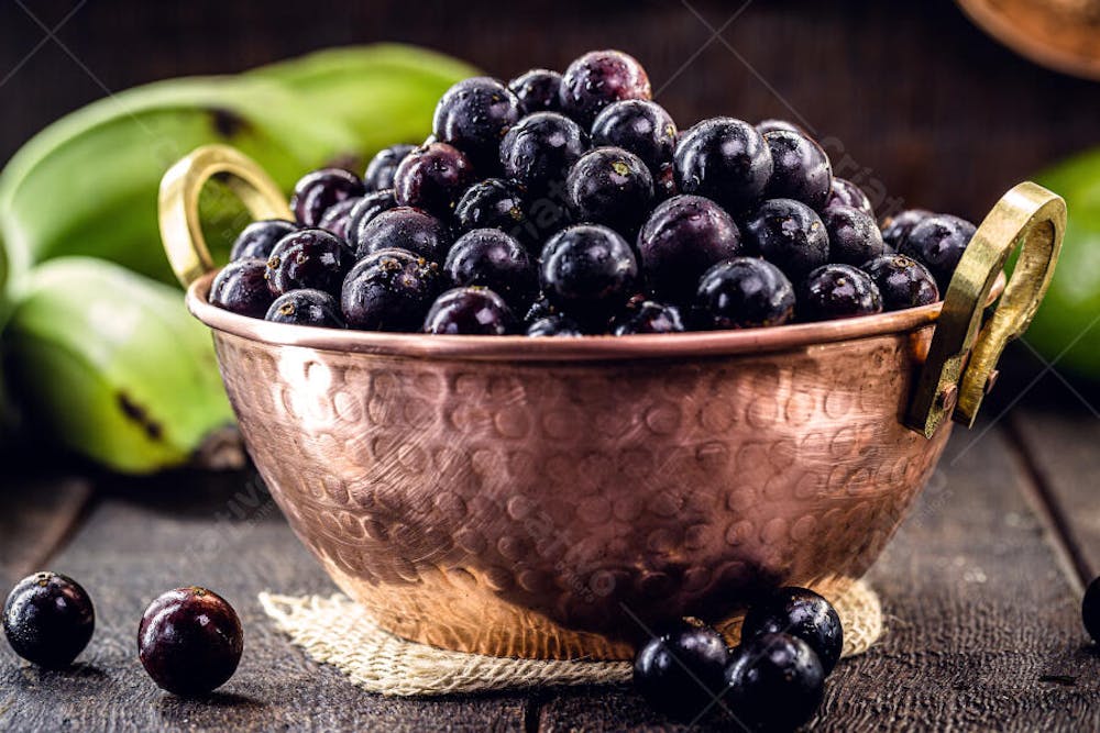 Fresh jaboticaba berries in copper bowl on rustic wood with green ...